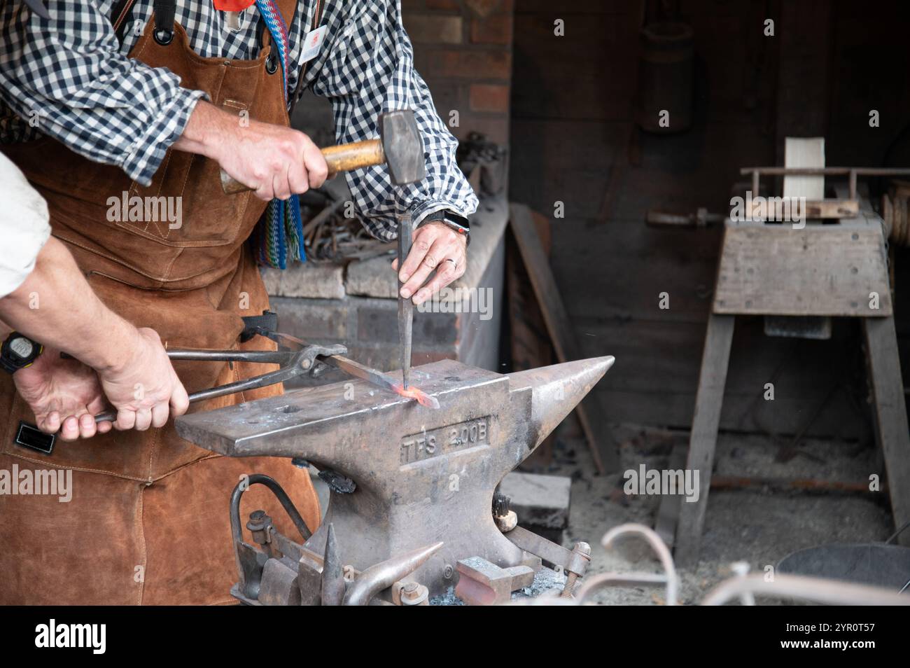 Photo of two blacksmiths hands working with hot metal making a tool on ...
