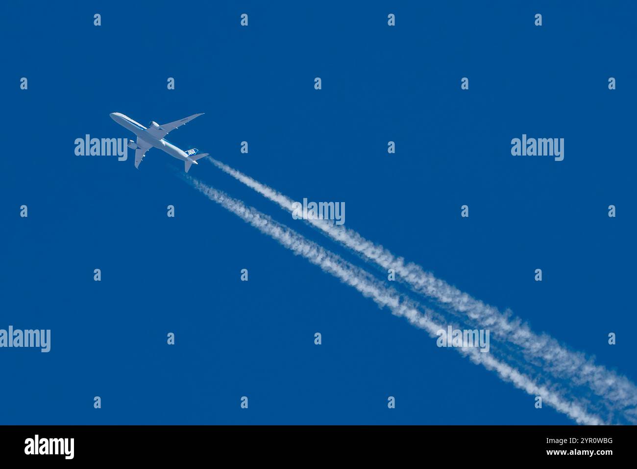 Commercial airplane with jet stream overhead view with blue background ...