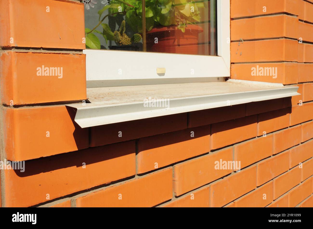 Install white metal window sill on the brick house Stock Photo - Alamy