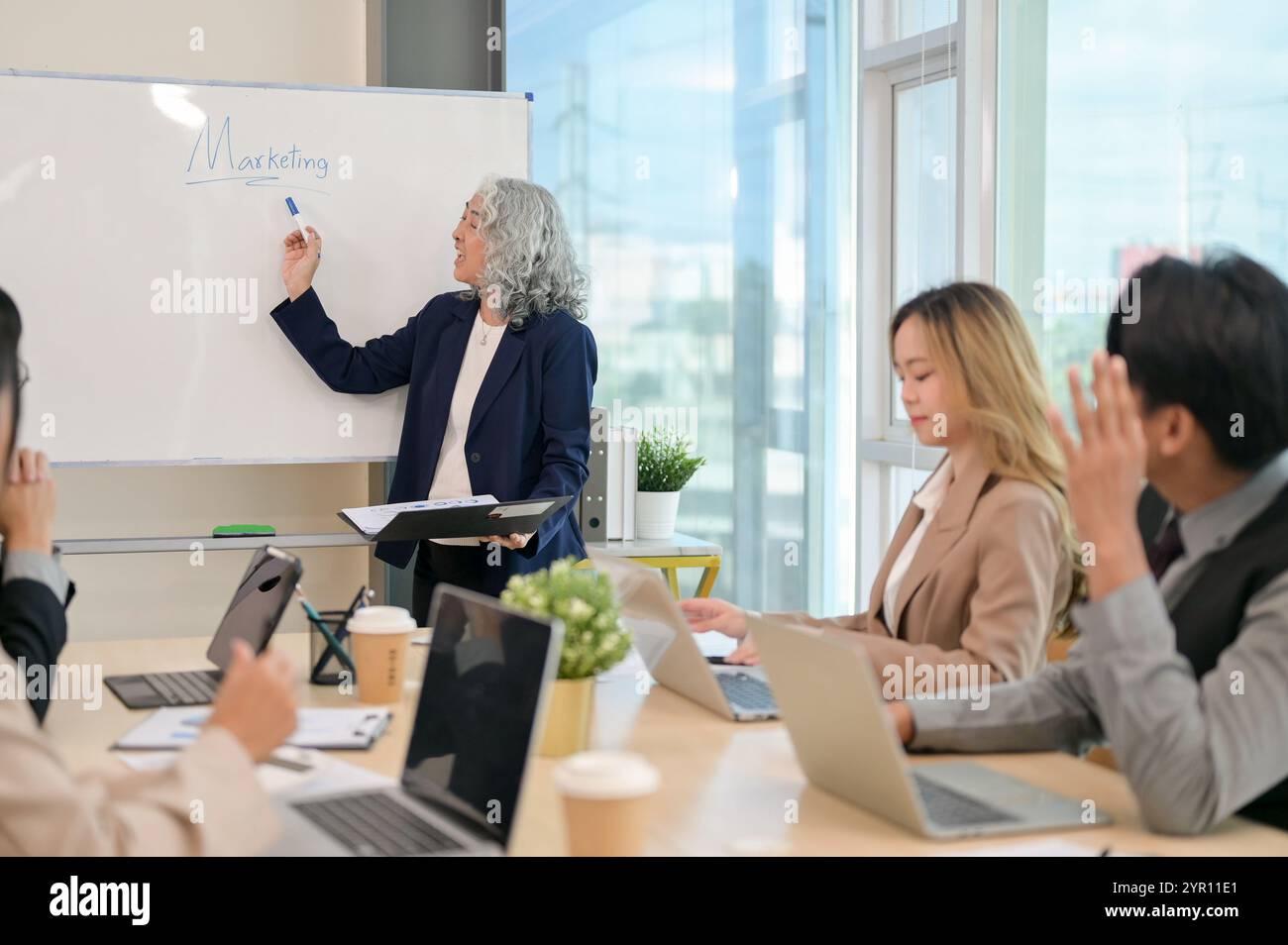 A professional Asian senior female CEO stands in front of a whiteboard ...