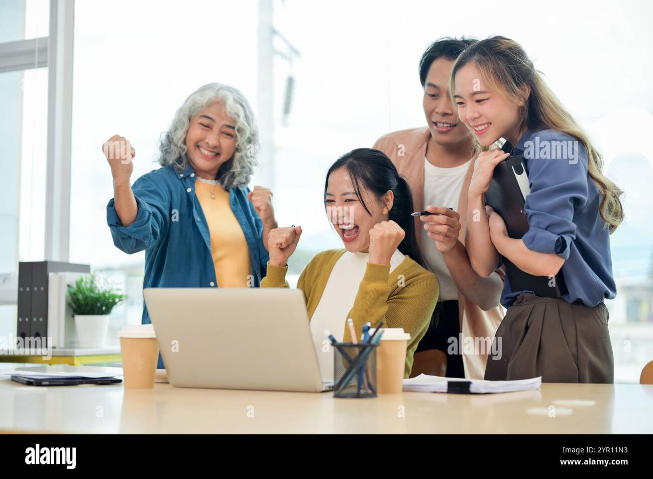 A cheerful Asian startup team celebrates their project success together ...