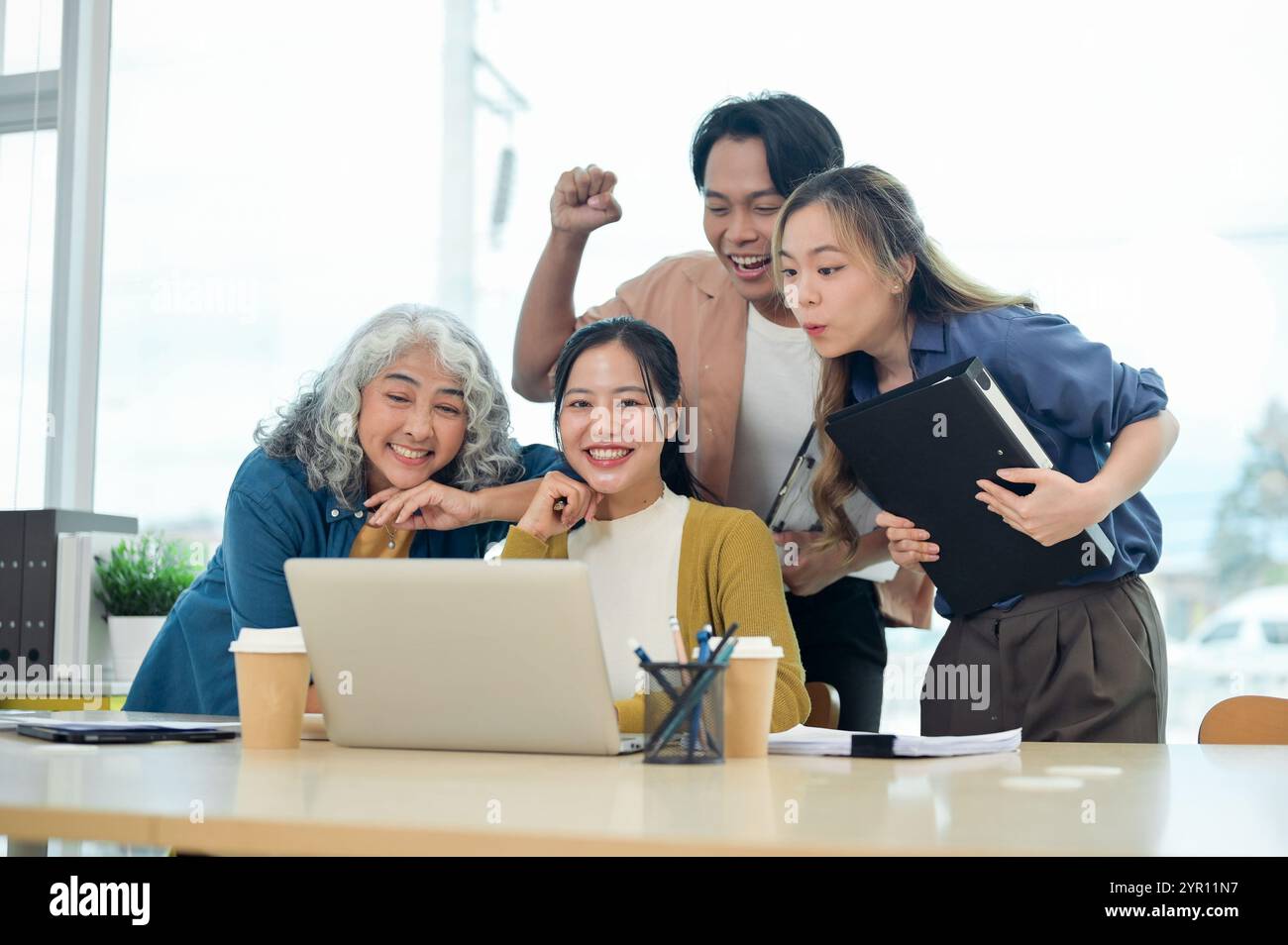 A cheerful Asian startup team celebrates their project success together ...