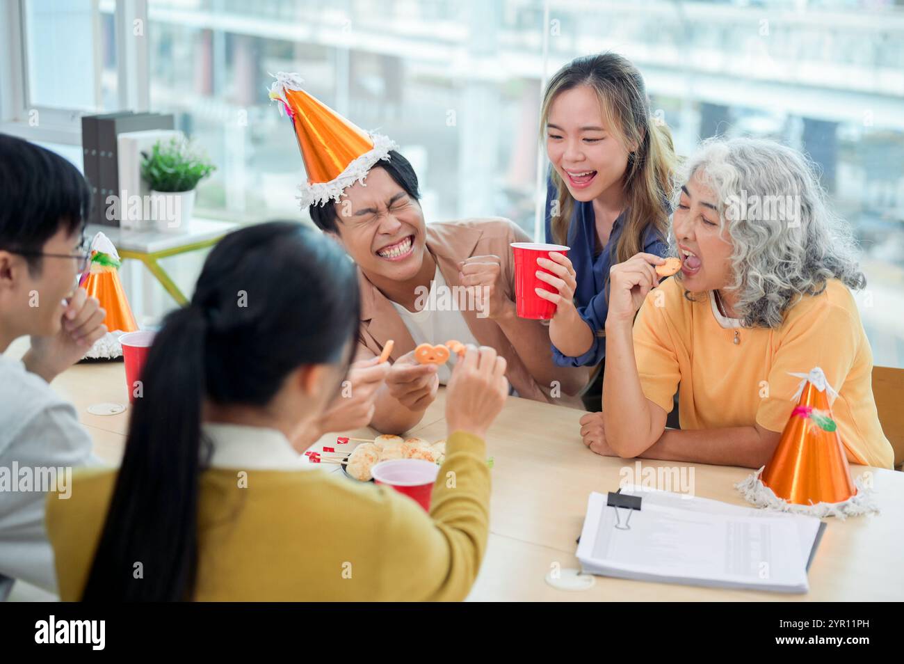 A group of joyful Asian diverse startup businesspeople celebrate in the ...