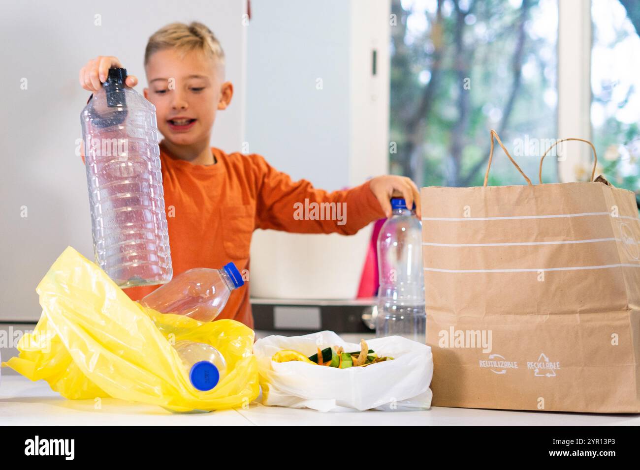Child putting plastic bottles into yellow bag, learning about recycling ...