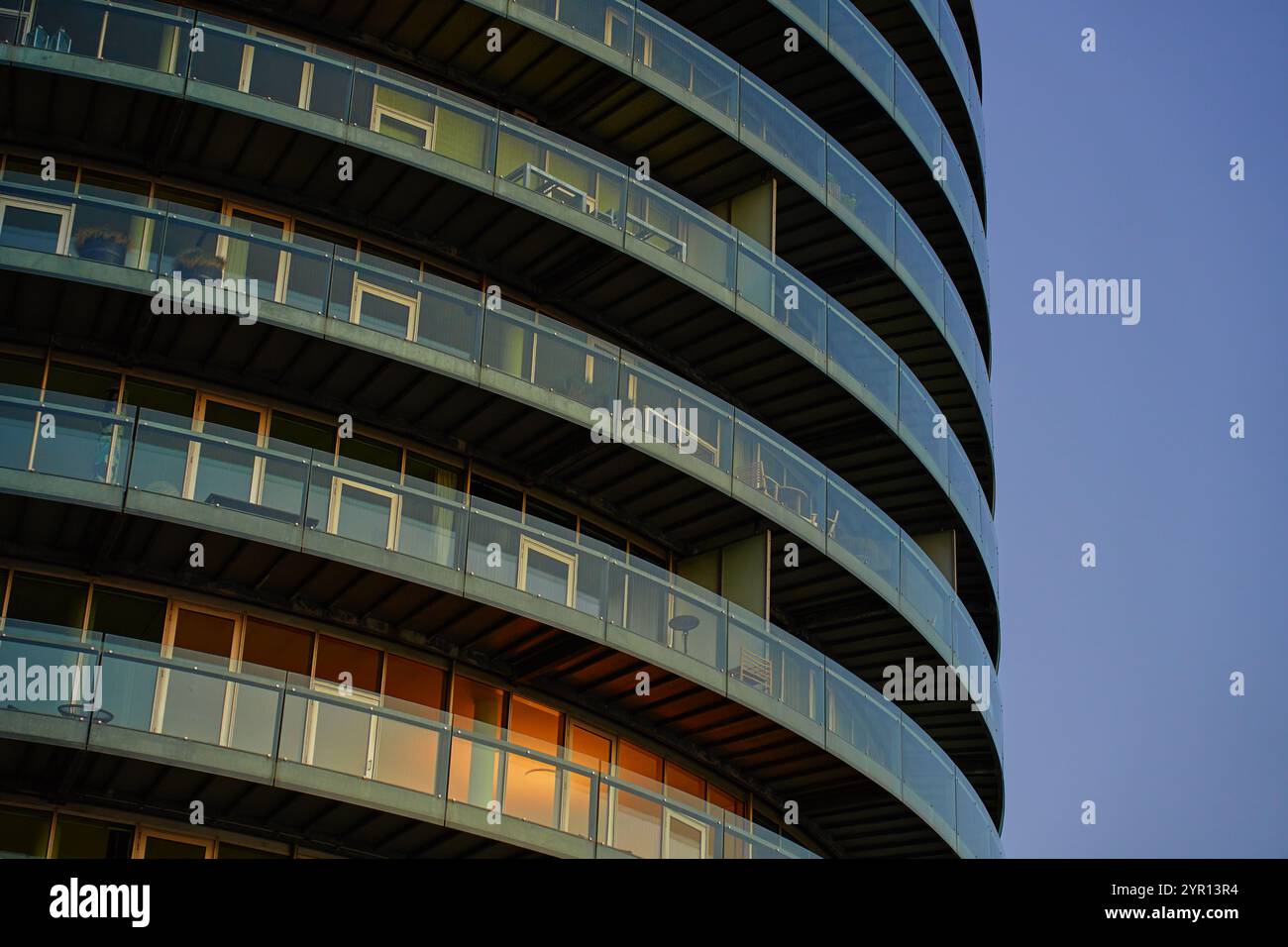 Modern round residential building with balconies at sunset ...