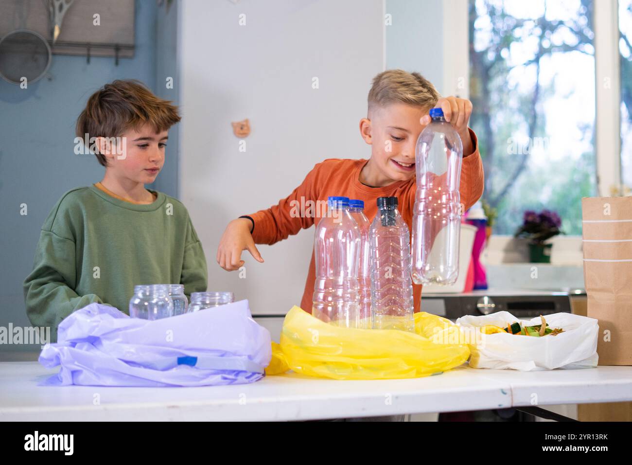 Two brothers separating plastic and glass waste in different garbage ...