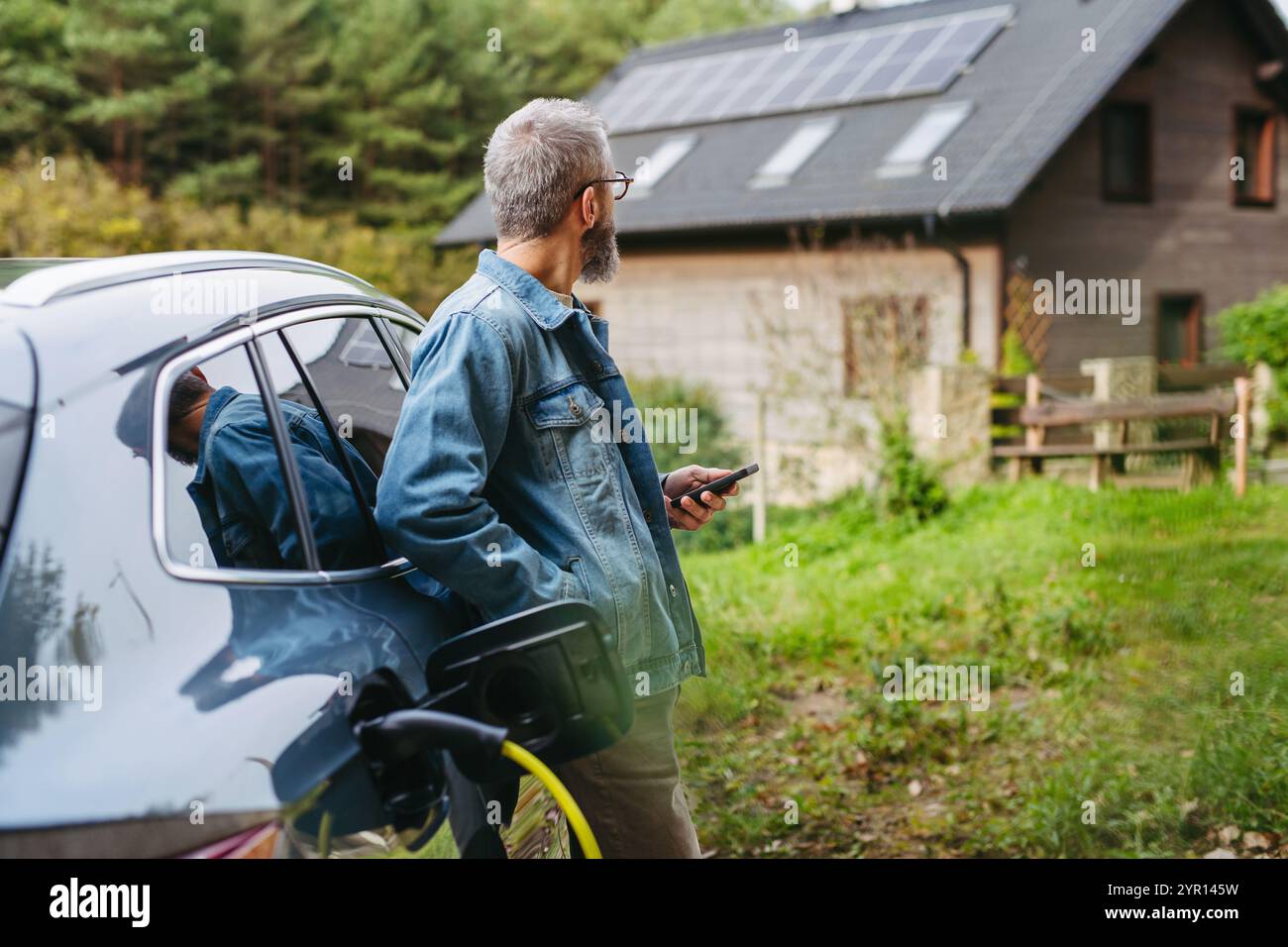 Man charging electric car in front of his house with solar panel system ...