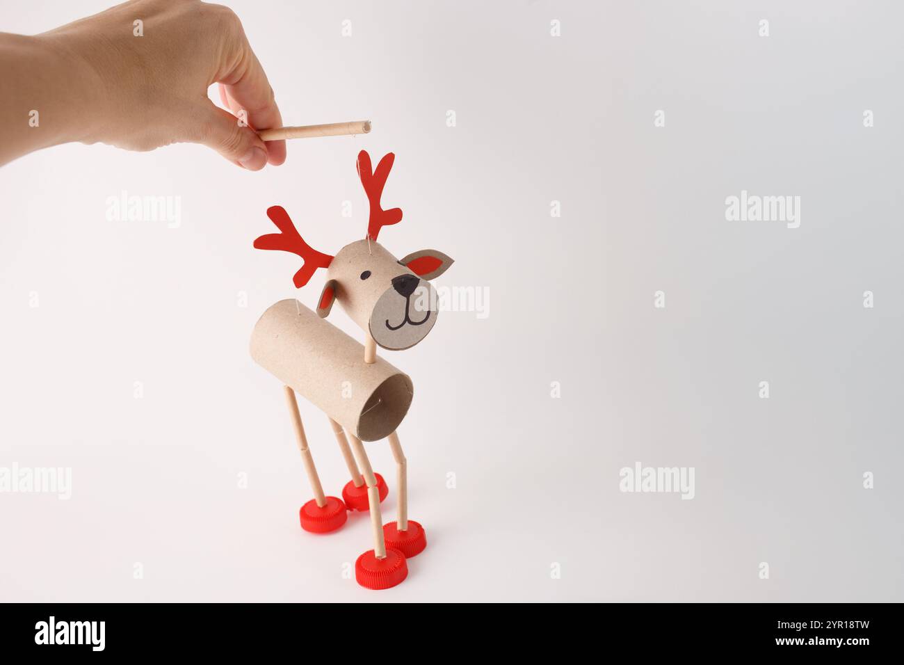 Hand holding DIY reindeer puppet made from cardboard tubes, red plastic ...
