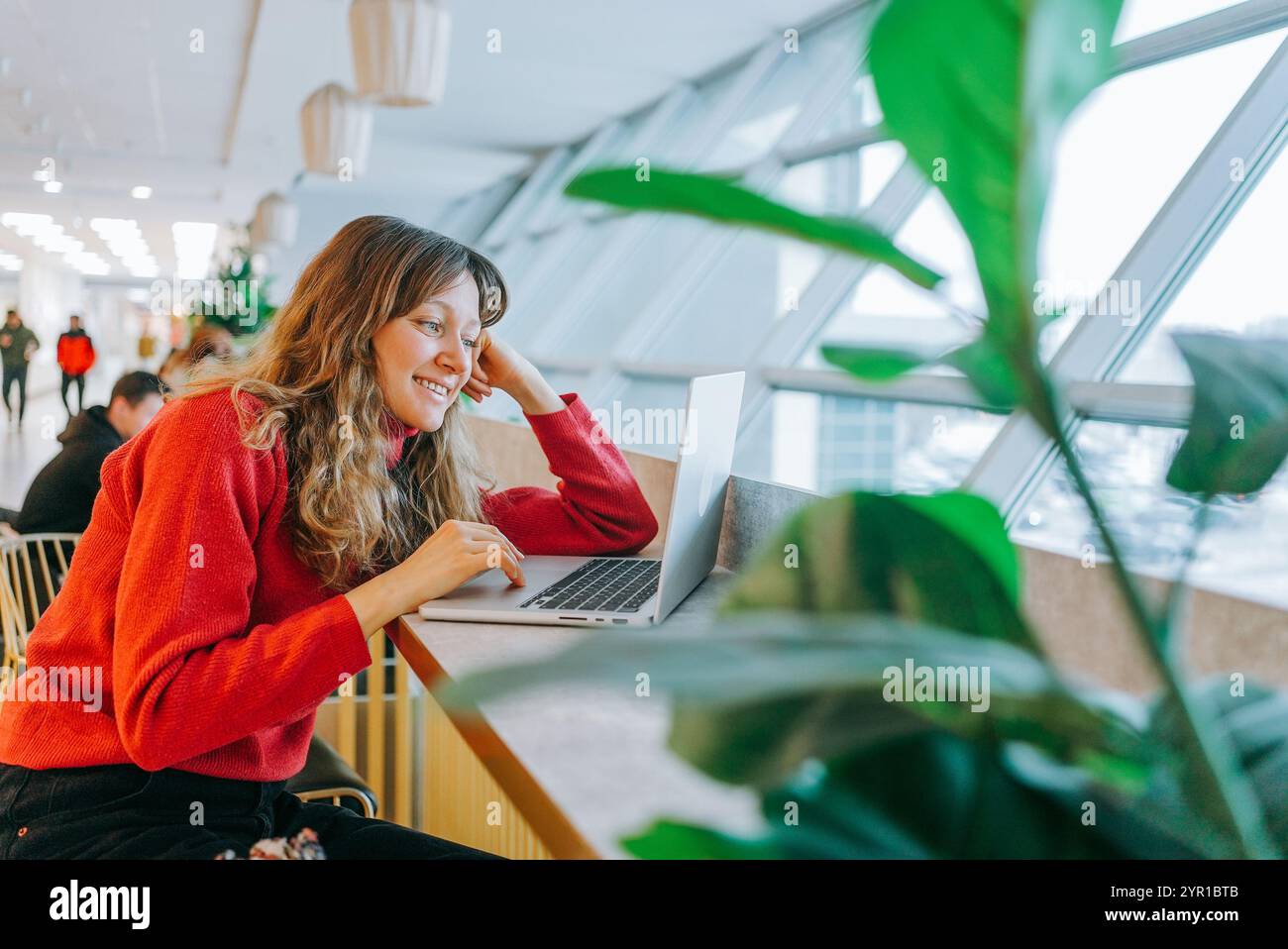 Young woman working remotely, using laptop in public coworking space ...