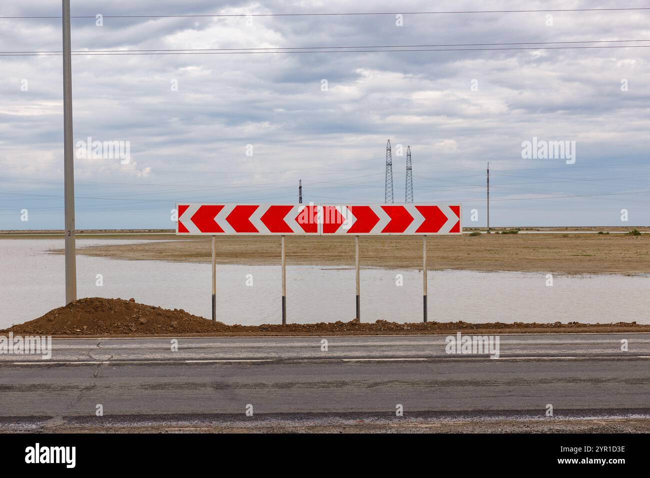 Red arrow signs warn drivers of a sharp curve ahead on a road adjacent ...