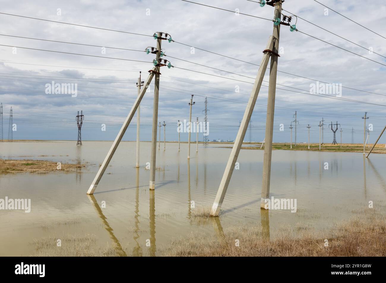 Standing water surrounds power poles in a flat landscape, showing the ...