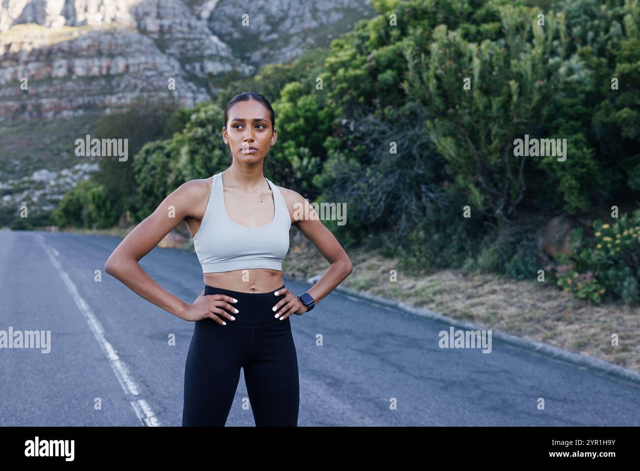 Confident female runner standing on an abandoned road and looking away ...