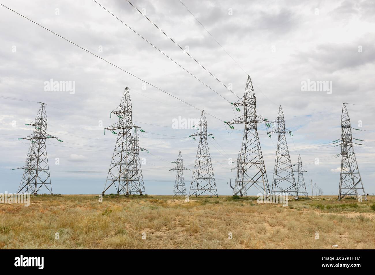 Tall electricity transmission towers rise over the flat terrain under a ...