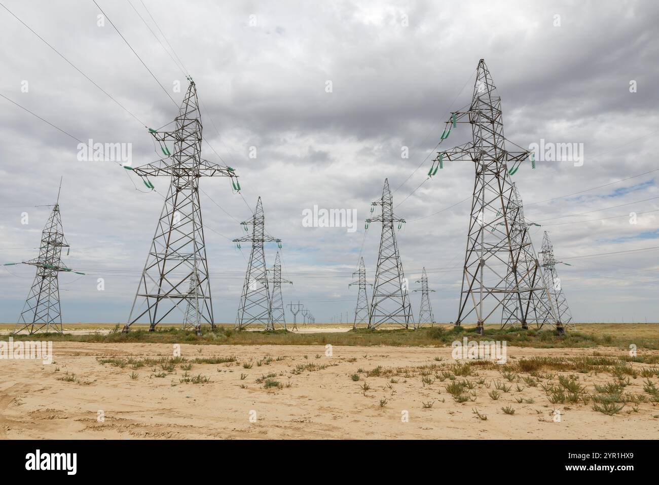 Rows of tall power towers stand against a backdrop of a cloudy sky, highlighting the vast, open ...