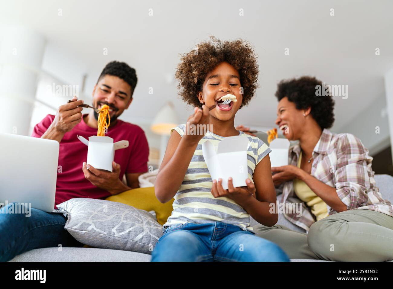 Happy african family eating at living room and enjoying time together ...