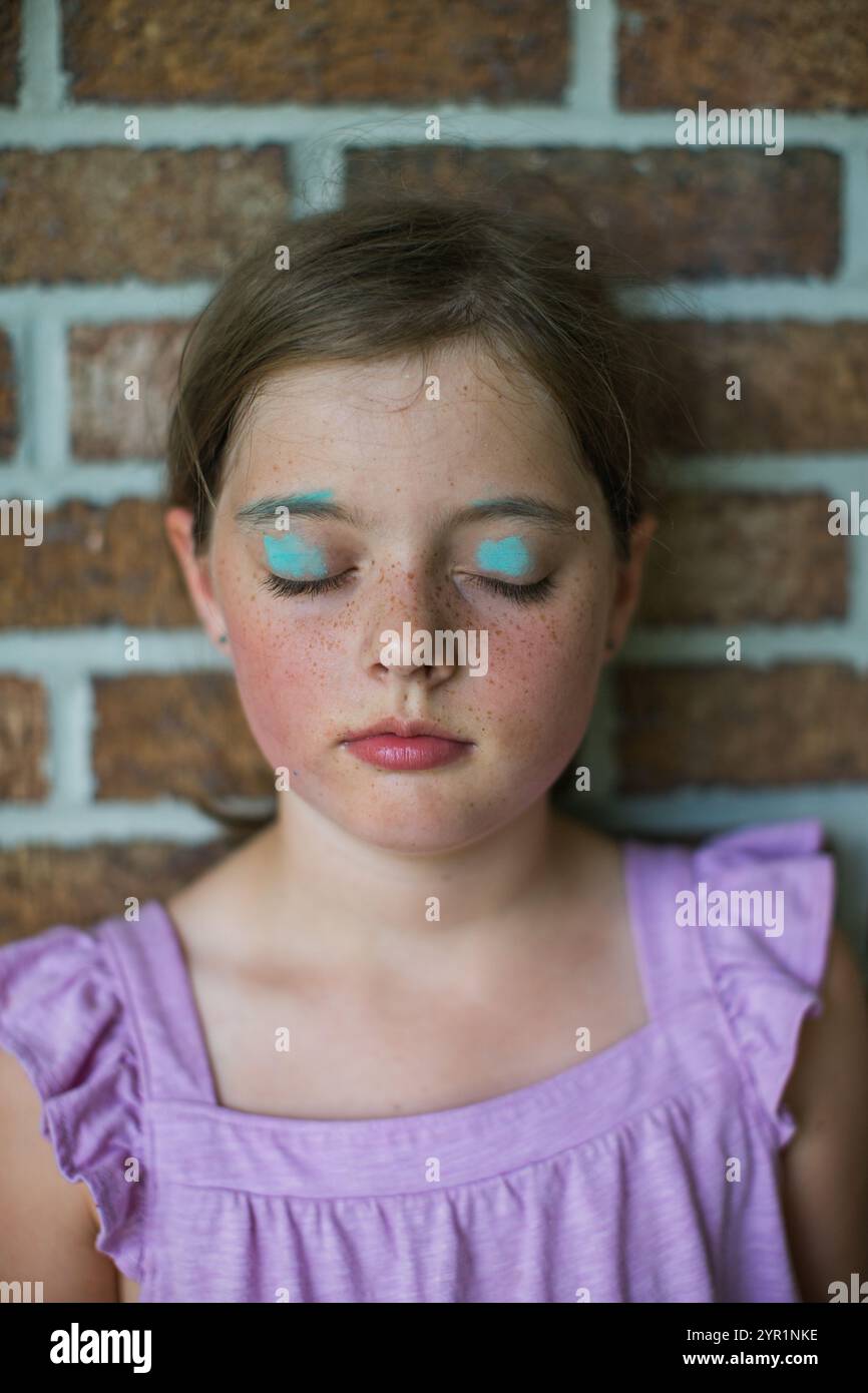 young girl with freckles and turquoise eye shadow with eyes closed ...