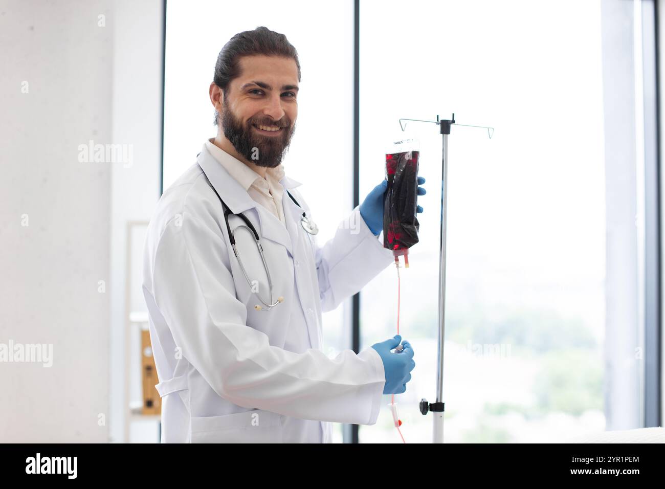Male doctor with beard and long hair in white coat holds dropper with ...
