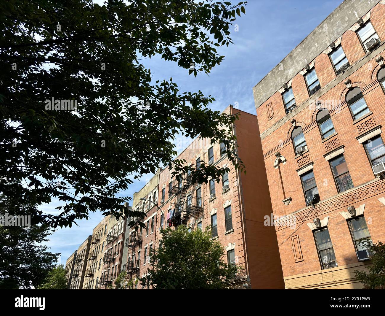 Row of brick apartment buildings with fire escapes under blue sky Stock ...