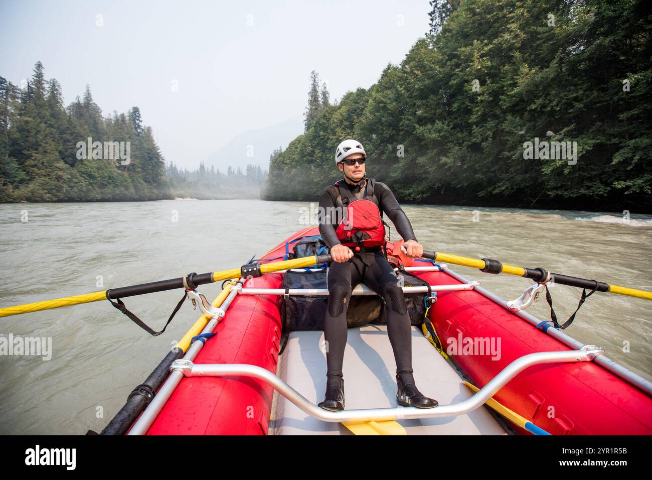 Man rowing oar frame raft on scenic river, shore lined with trees Stock ...