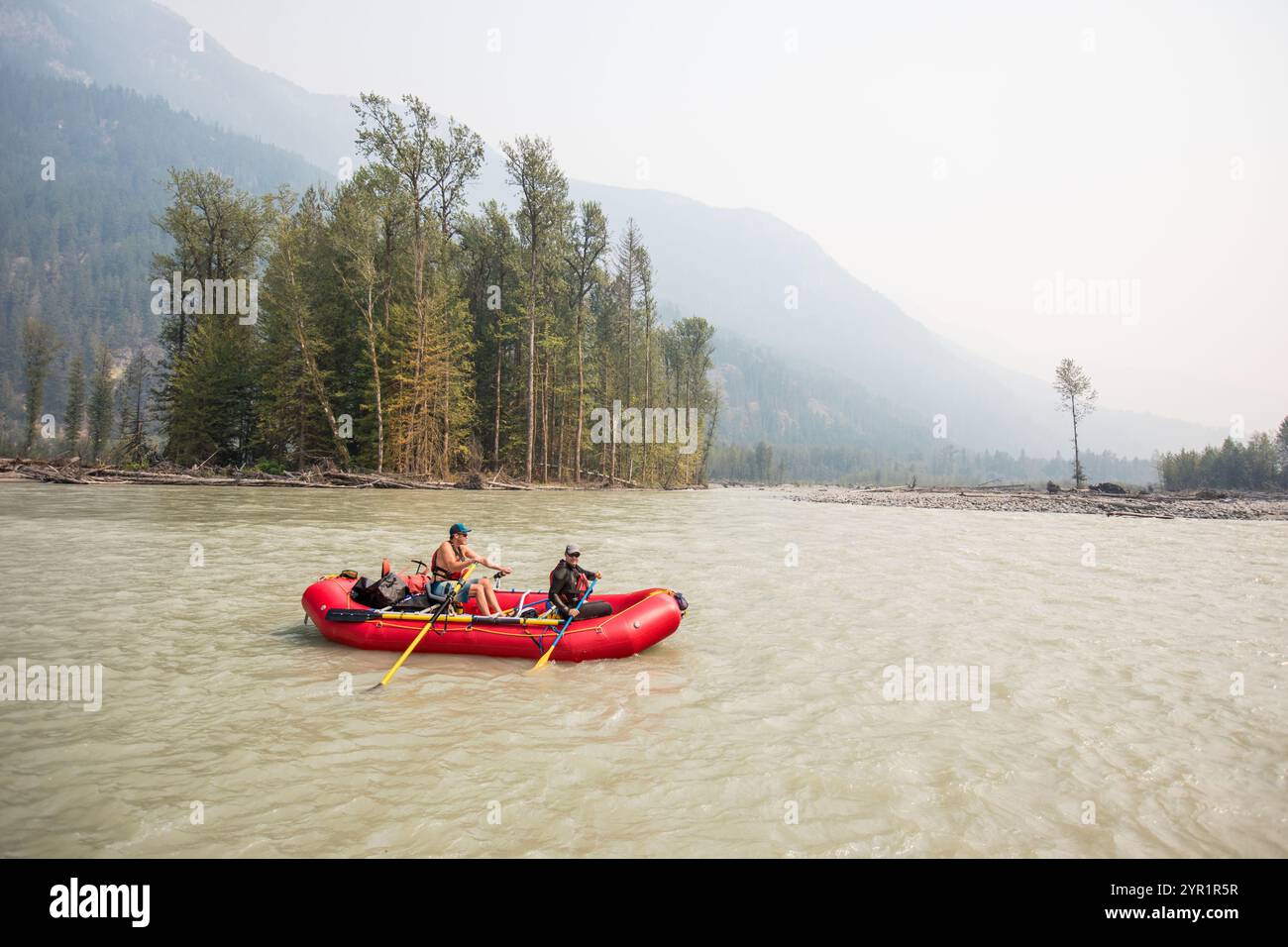 Two men paddling on red raft boat, forest fire smoke Stock Photo - Alamy