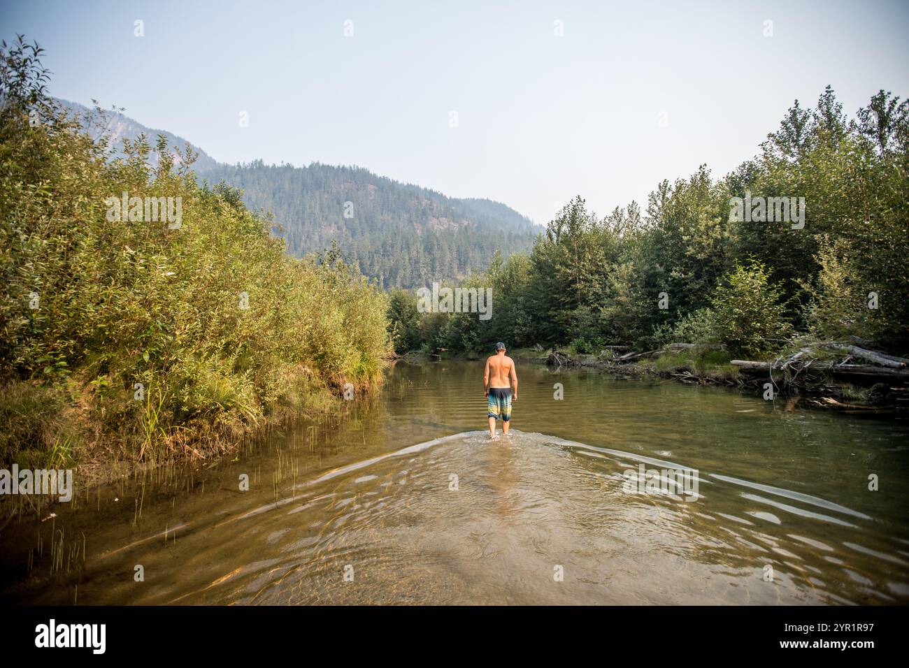 First Nations man wading in shallow river, connecting to the land Stock ...