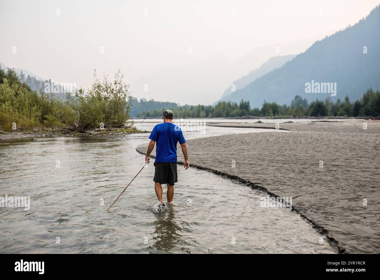 Rear view of man walking river next to the shore Stock Photo - Alamy
