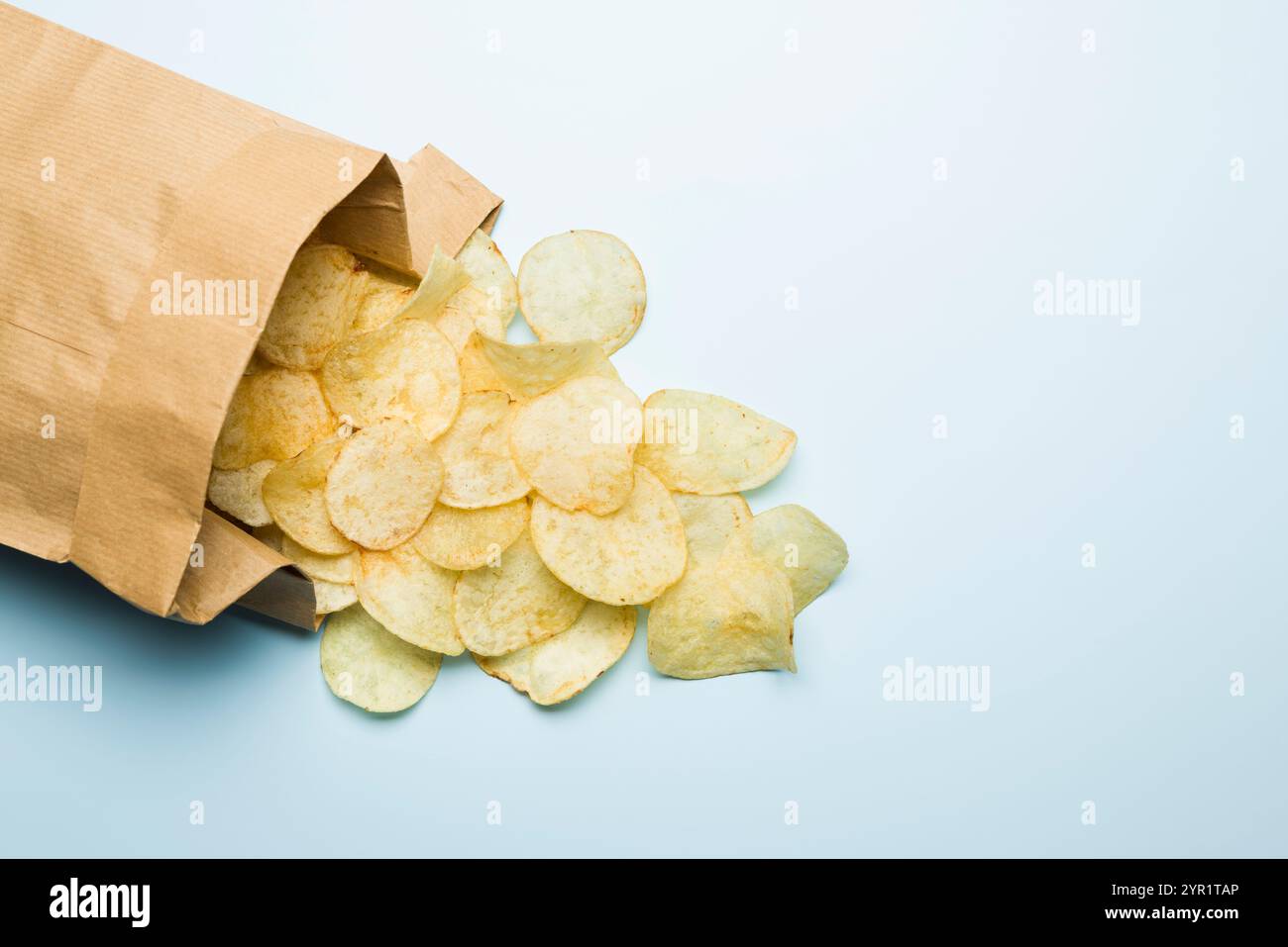 Paper bag with potato chips spilled on blue background Stock Photo - Alamy