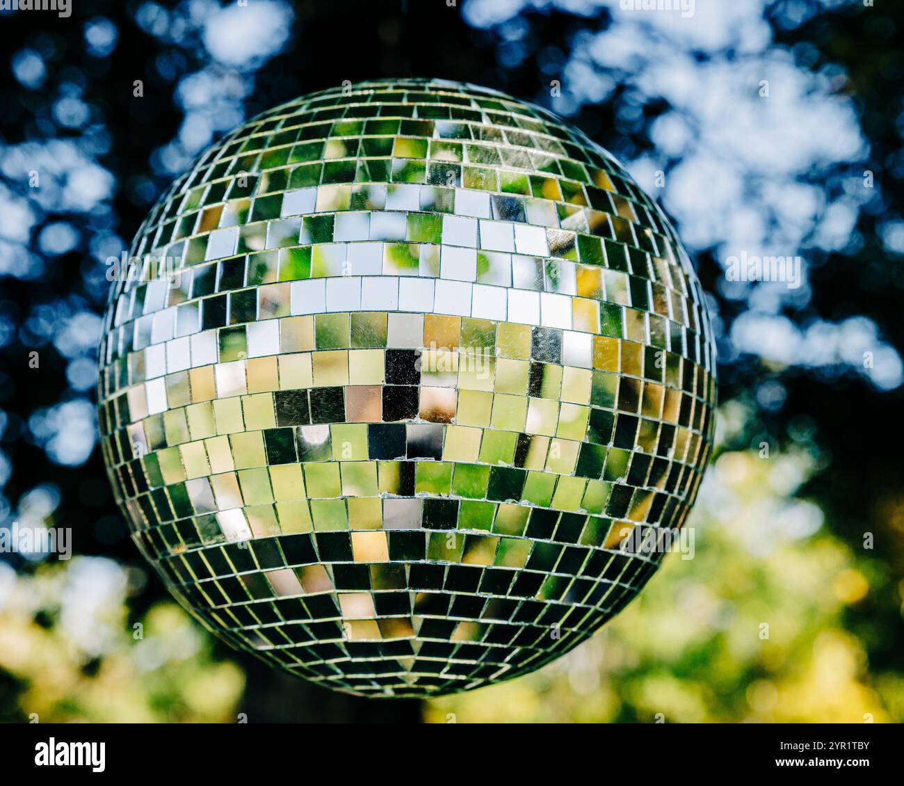 Large disco ball hanging outdoors with green and blue hues Stock Photo ...