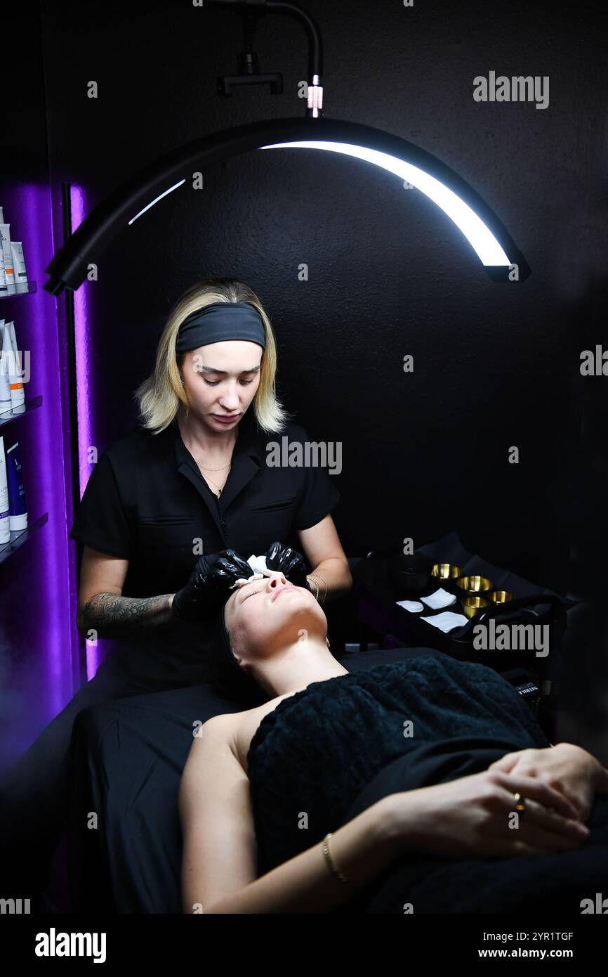 Spa professional performing detailed facial treatment under sof Stock ...