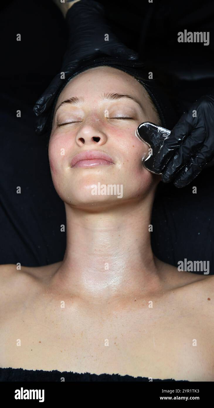 Woman receiving a gua sha facial massage for relaxation and skin Stock ...