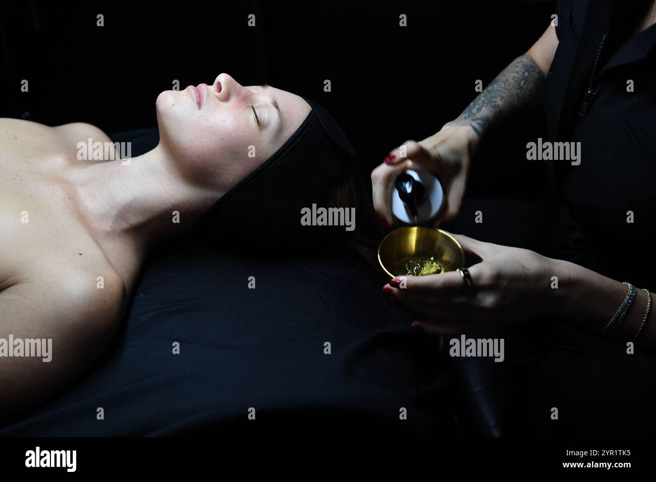 Woman receiving a facial treatment with golden oil preparation Stock ...