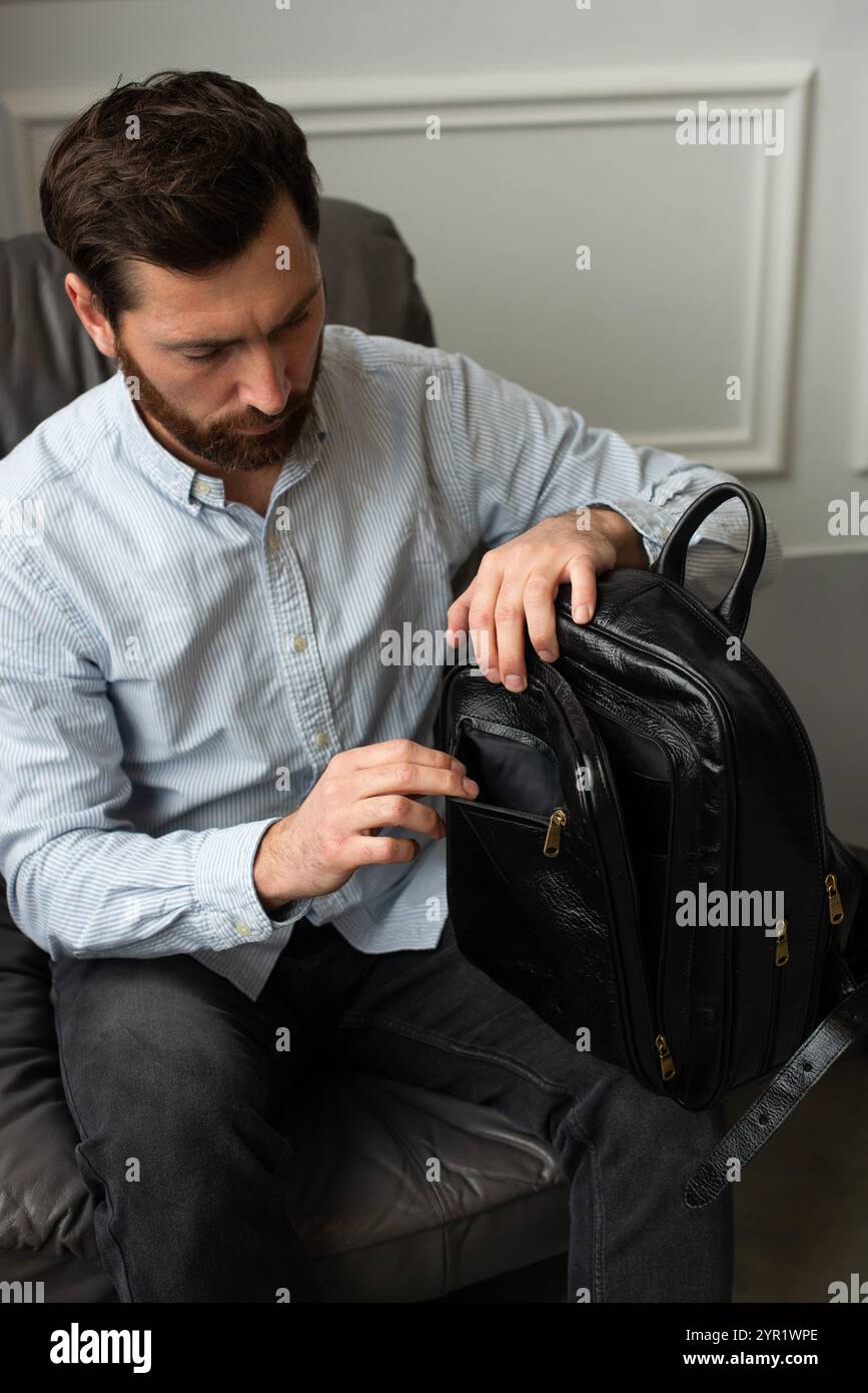 A man is comfortably sitting in a chair, resting with a leather ...