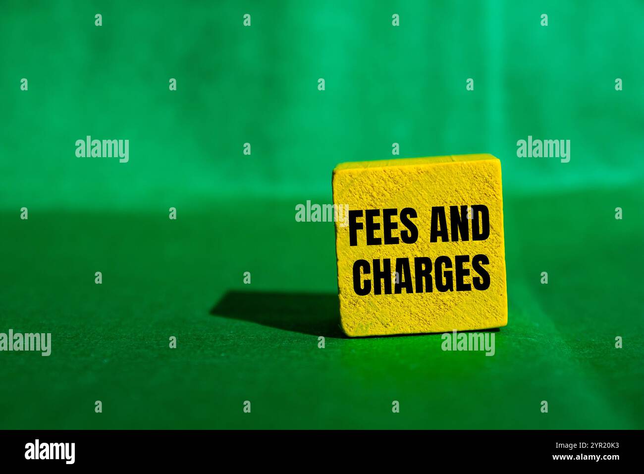 Fees and charges message written on yellow wooden cube with green ...