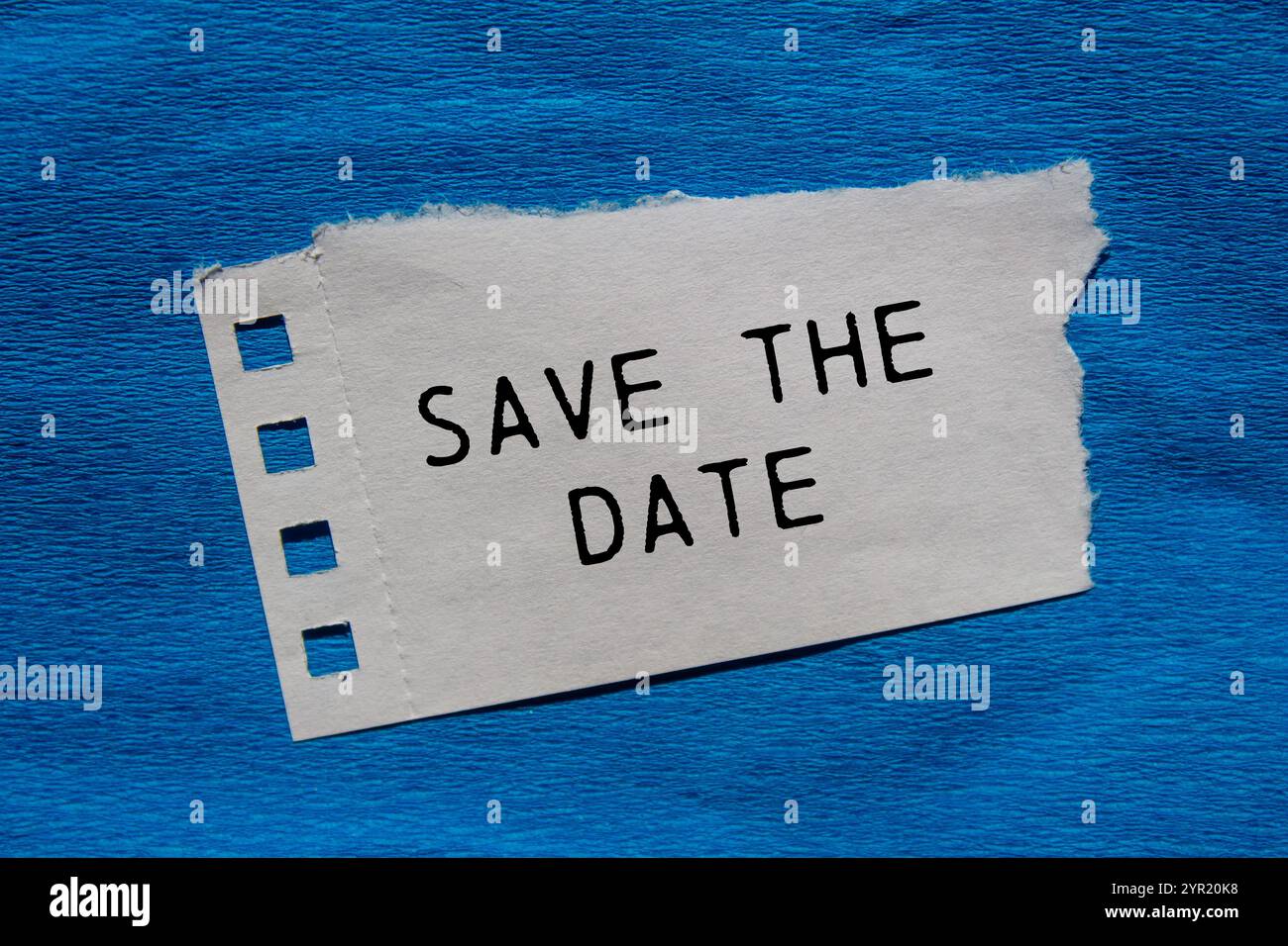 Save the date message written on ripped torn paper piece with blue ...