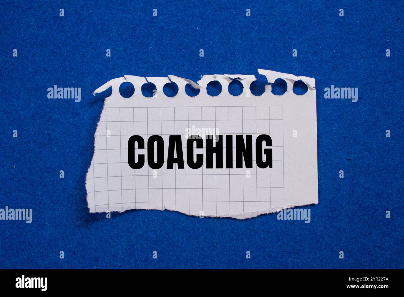 Coaching message written on ripped torn paper piece with blue background. Conceptual coaching ...