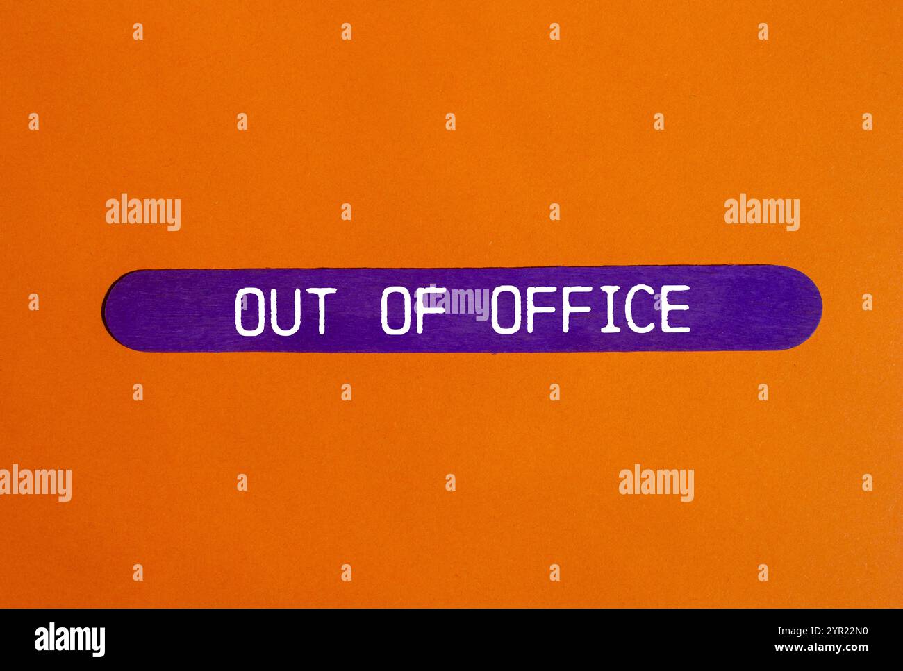 Out of office message written on purple wooden stick with orange ...
