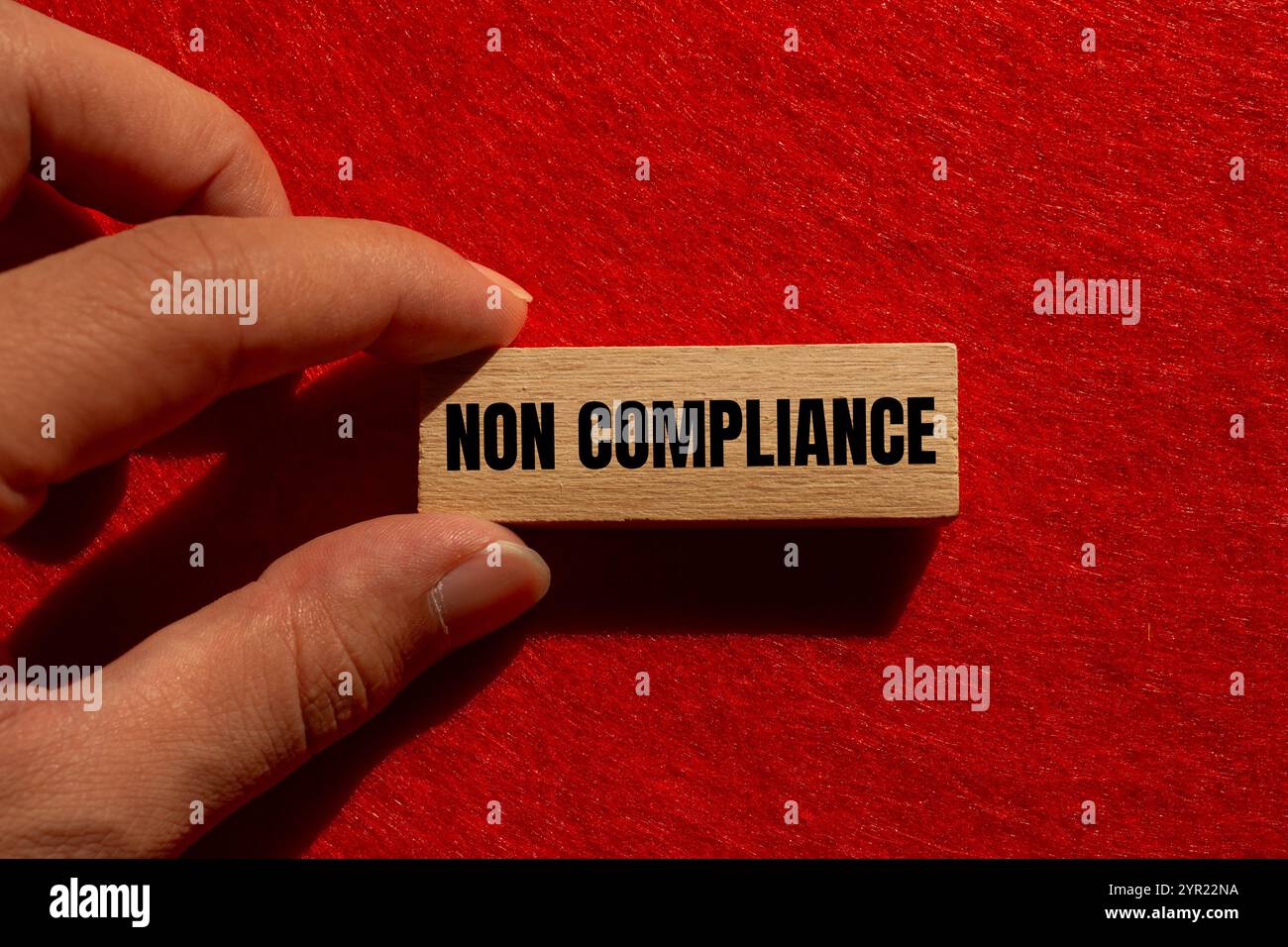 Non compliance message written on wooden block with red background. Conceptual non compliance ...