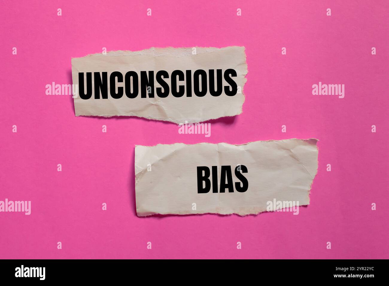 Unconscious bias message written on ripped paper pieces with pink background. Conceptual ...
