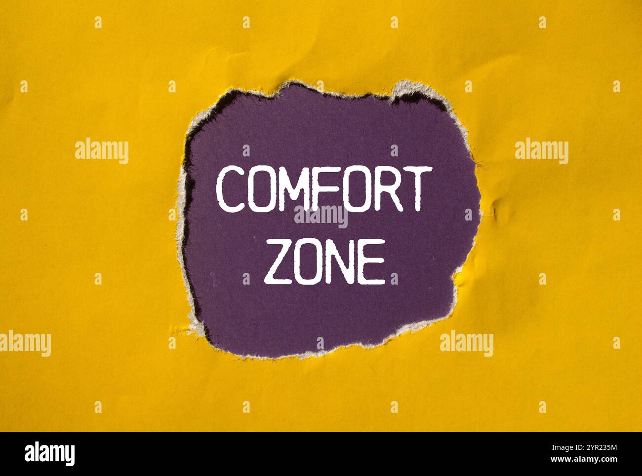 Comfort zone message written on ripped torn yellow paper with purple background. Conceptual ...