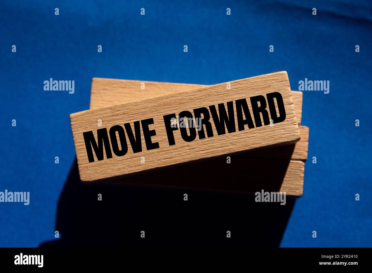 Move forward message written on wooden blocks with blue background. Conceptual move forward ...