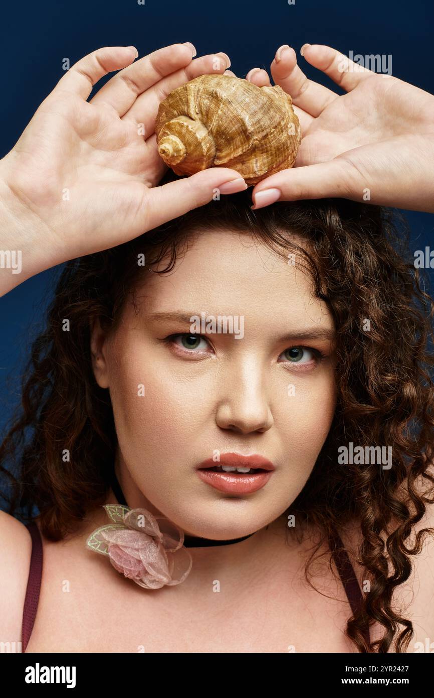 A stylish young woman poses confidently with a seashell balanced on her ...