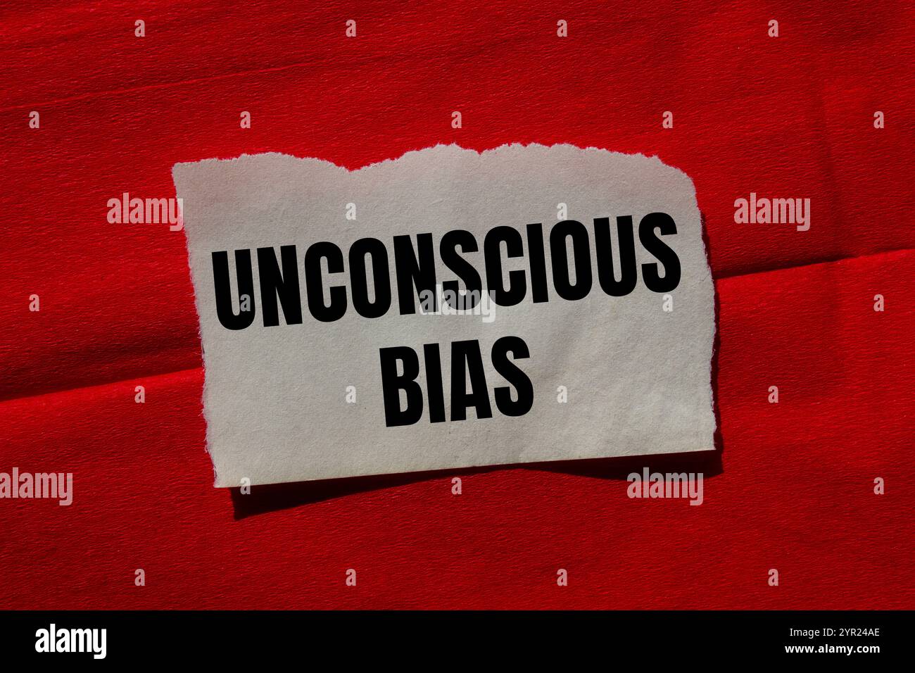 Unconscious bias message written on ripped torn paper piece on red background. Conceptual ...