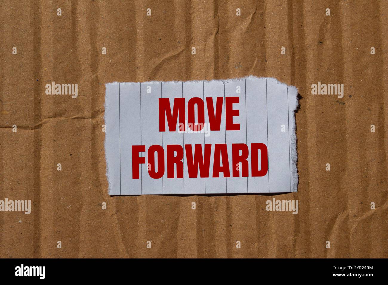 Move forward message written on ripped torn paper piece with cardboard paper background ...