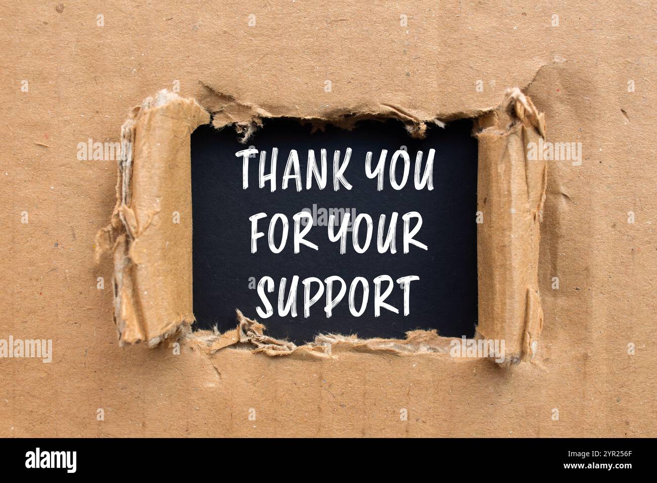 Thank you for your support message written on ripped torn cardboard paper with black background ...