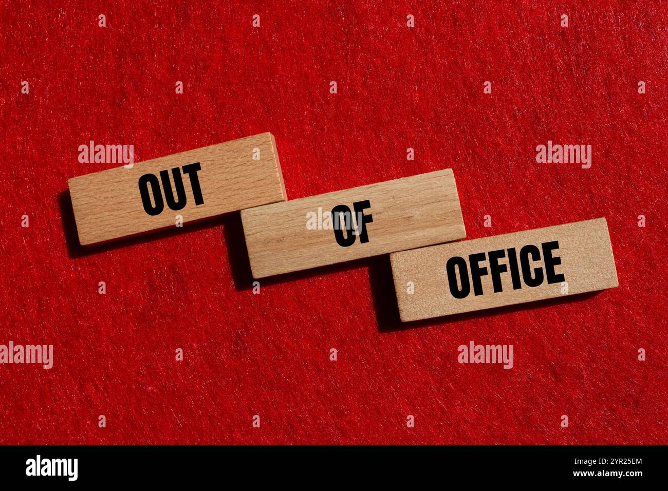 Out of office message written on wooden blocks with red background ...