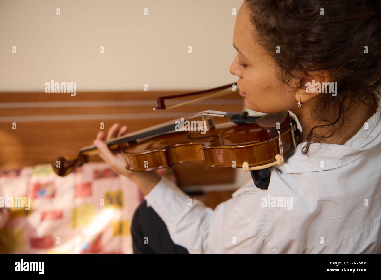 A woman is seen deeply focused on playing the violin, surrounded by a ...