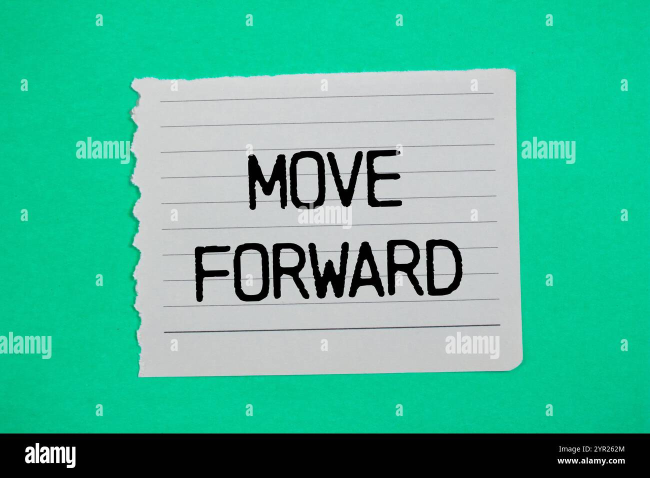 Move forward message written on ripped torn paper piece with green background. Conceptual move ...