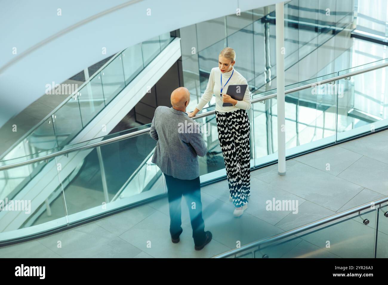 Two business professionals engage in conversation on an upper-floor ...