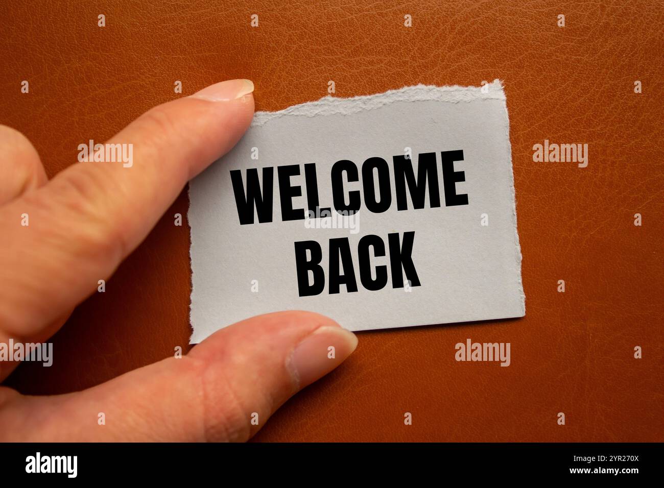 Welcome back message written on ripped torn paper piece with brown ...