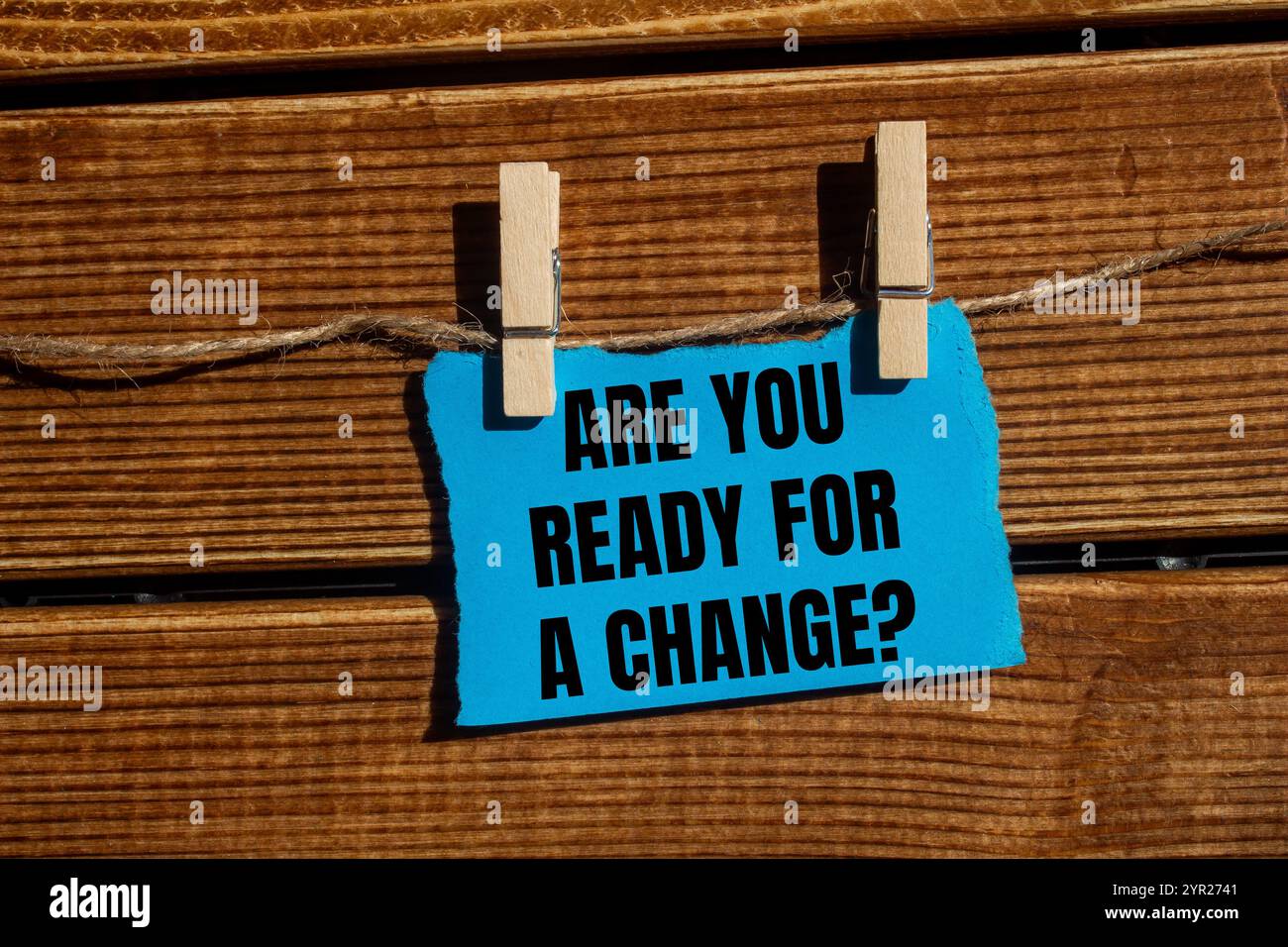 Are you ready for a change message written on ripped blue torn paper piece with wooden ...